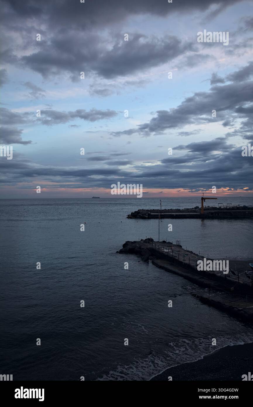 Sea stretching to the horizon with breakwaters on a cloudy nightfall ...