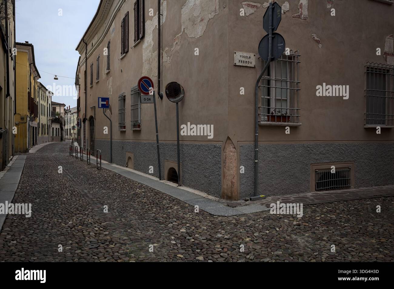 Crossing between cobbled streets partly in the shade at the corner of a ...