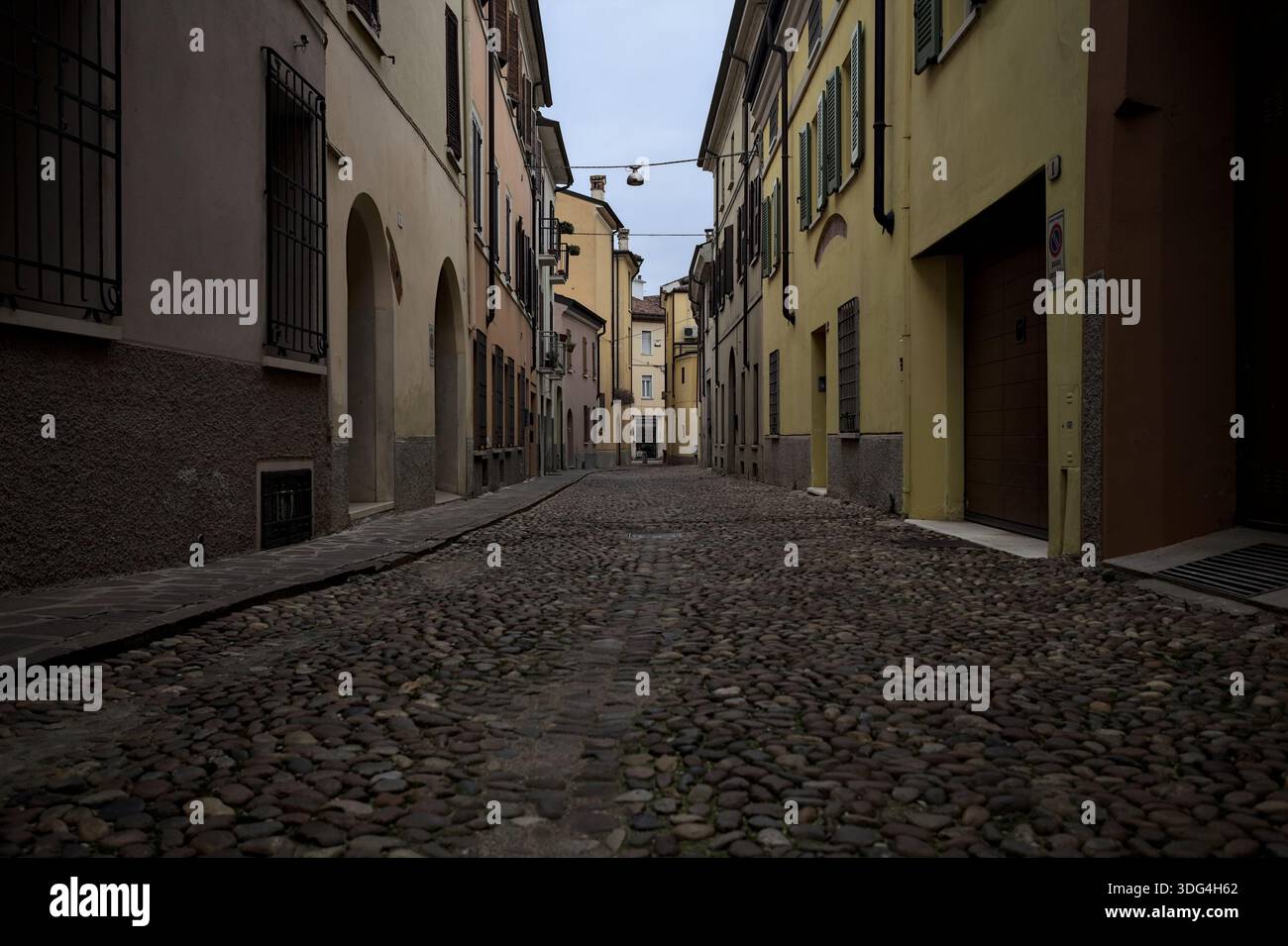 Cobbled alley that narrows at its end in an italian town on a cloudy ...