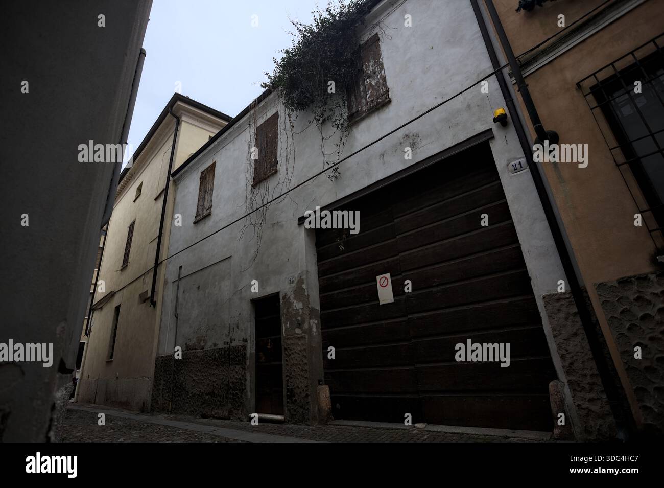 Worn out facade with a wooden gate and a creeper plant hanging from the ...
