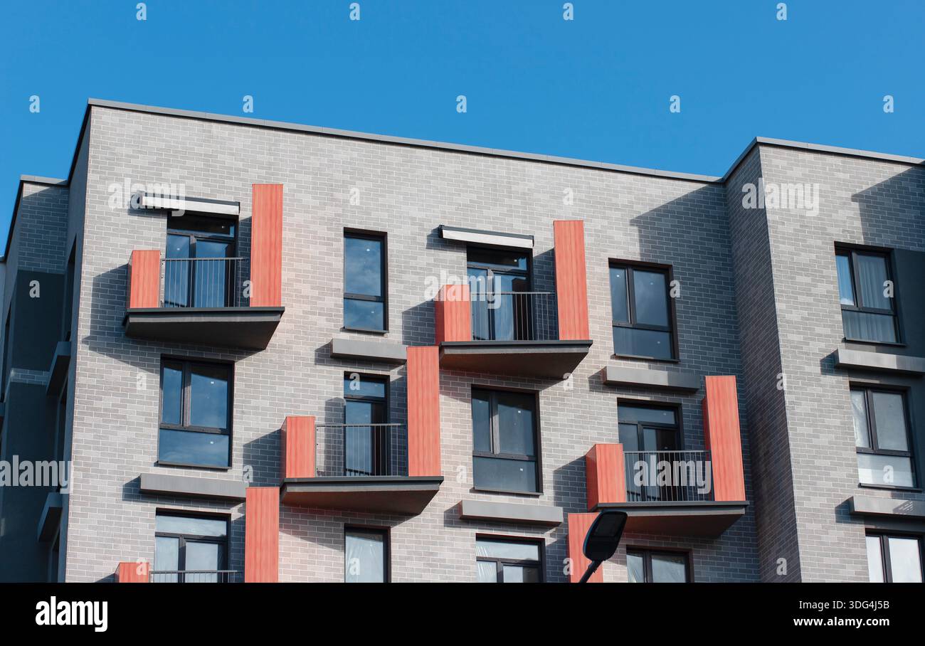 Modern residential building with gray brick facade, red vertical ...