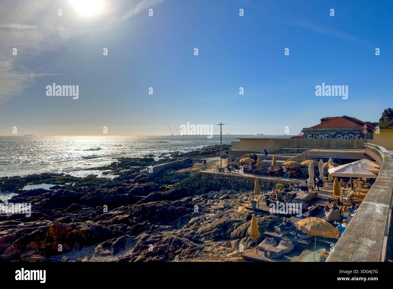 Seaside lounge and restaurant with sun umbrellas and people relaxing on ...
