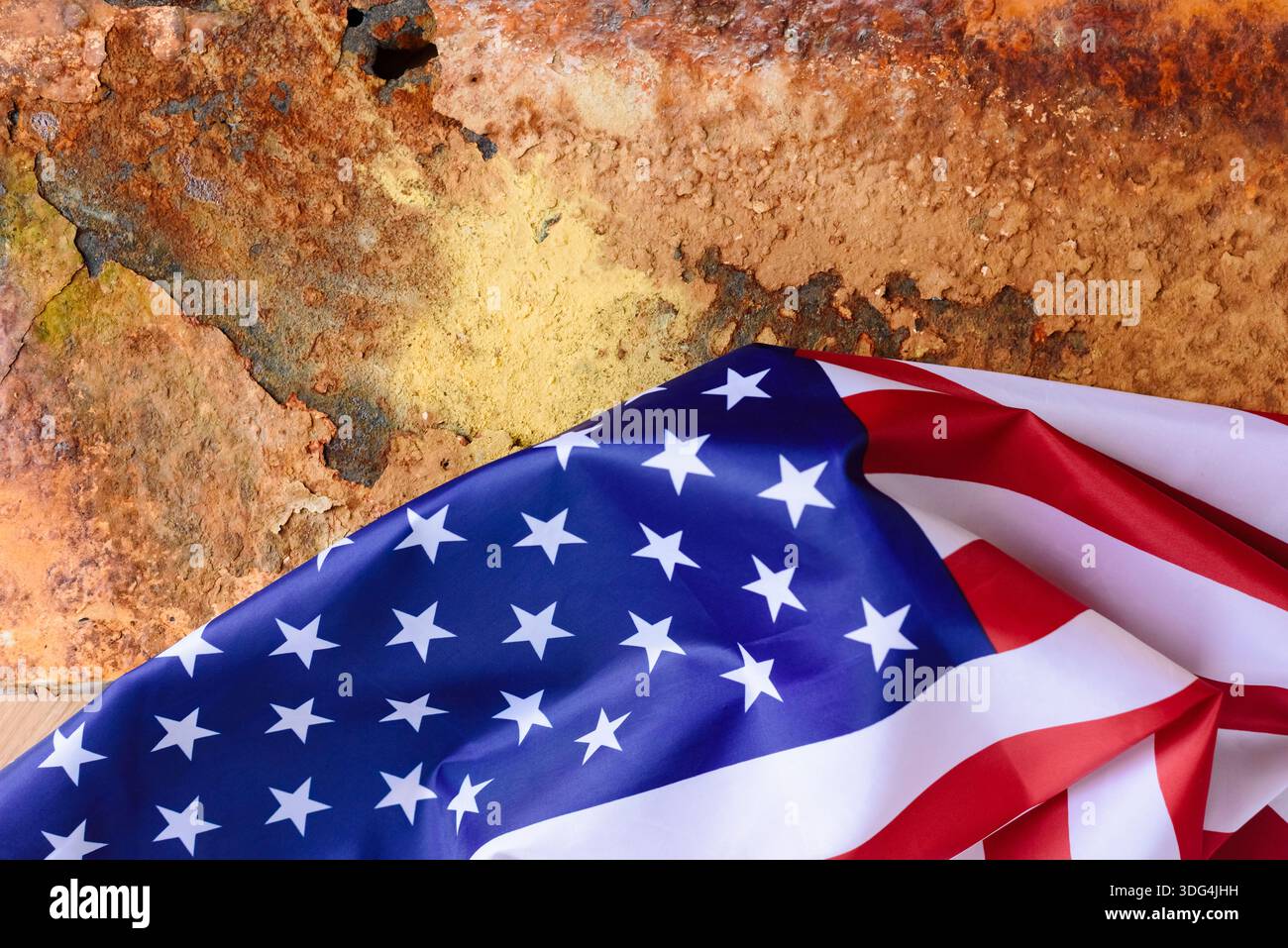 A USA flag appears wrinkled on an aged, rusty metal surface. The ...