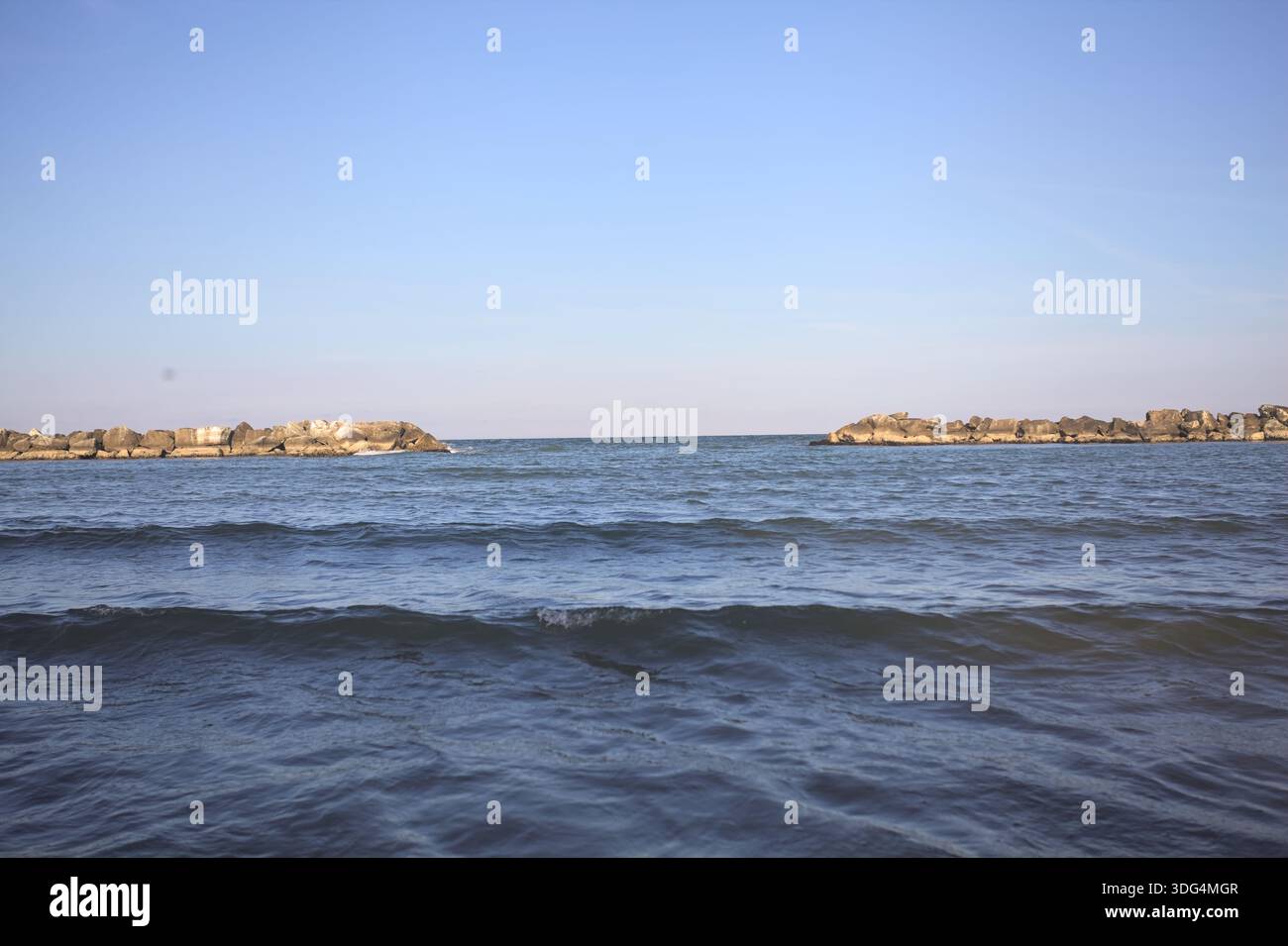 Breakwater on the horizon by the seaside at sunset Stock Photo - Alamy