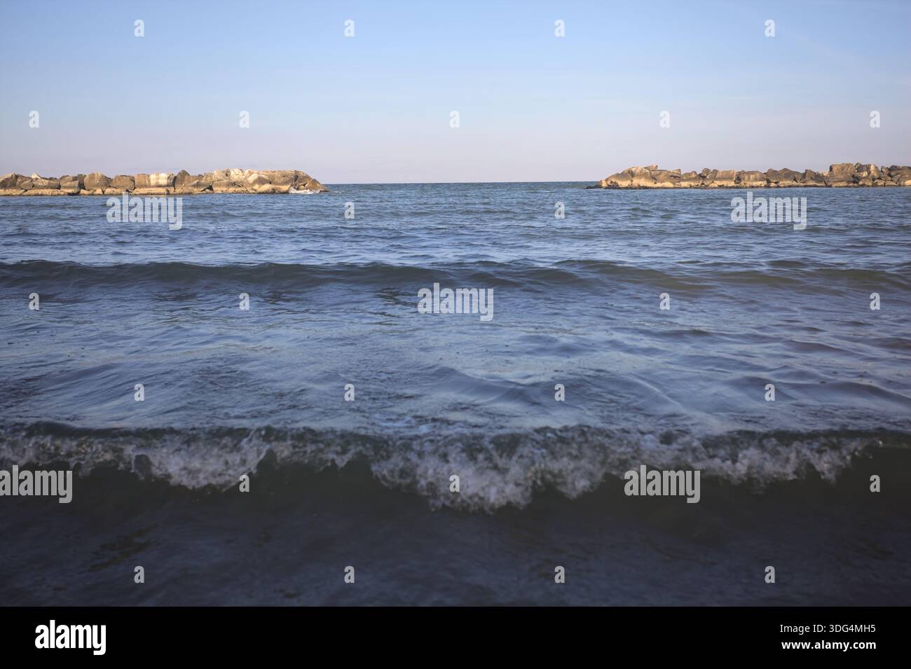 Breakwater on the horizon by the seaside at sunset Stock Photo - Alamy