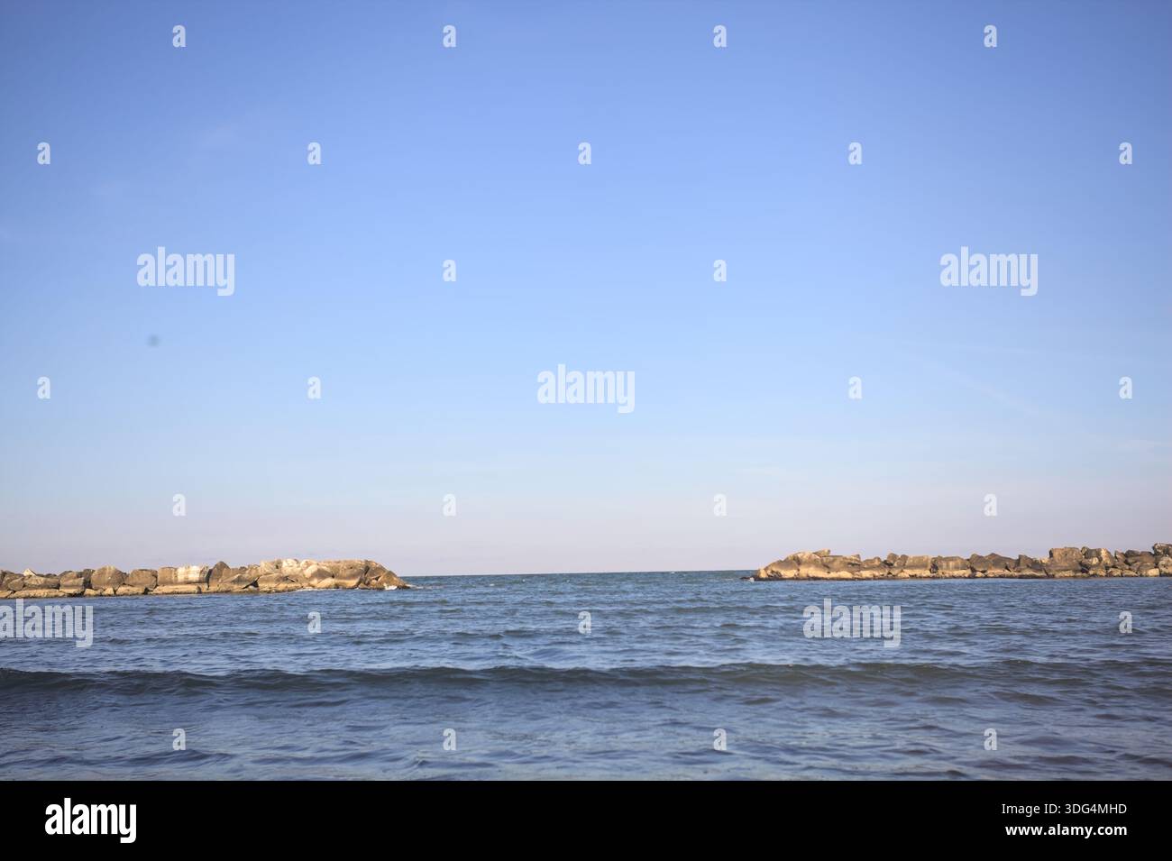 Breakwater on the horizon by the seaside at sunset Stock Photo - Alamy