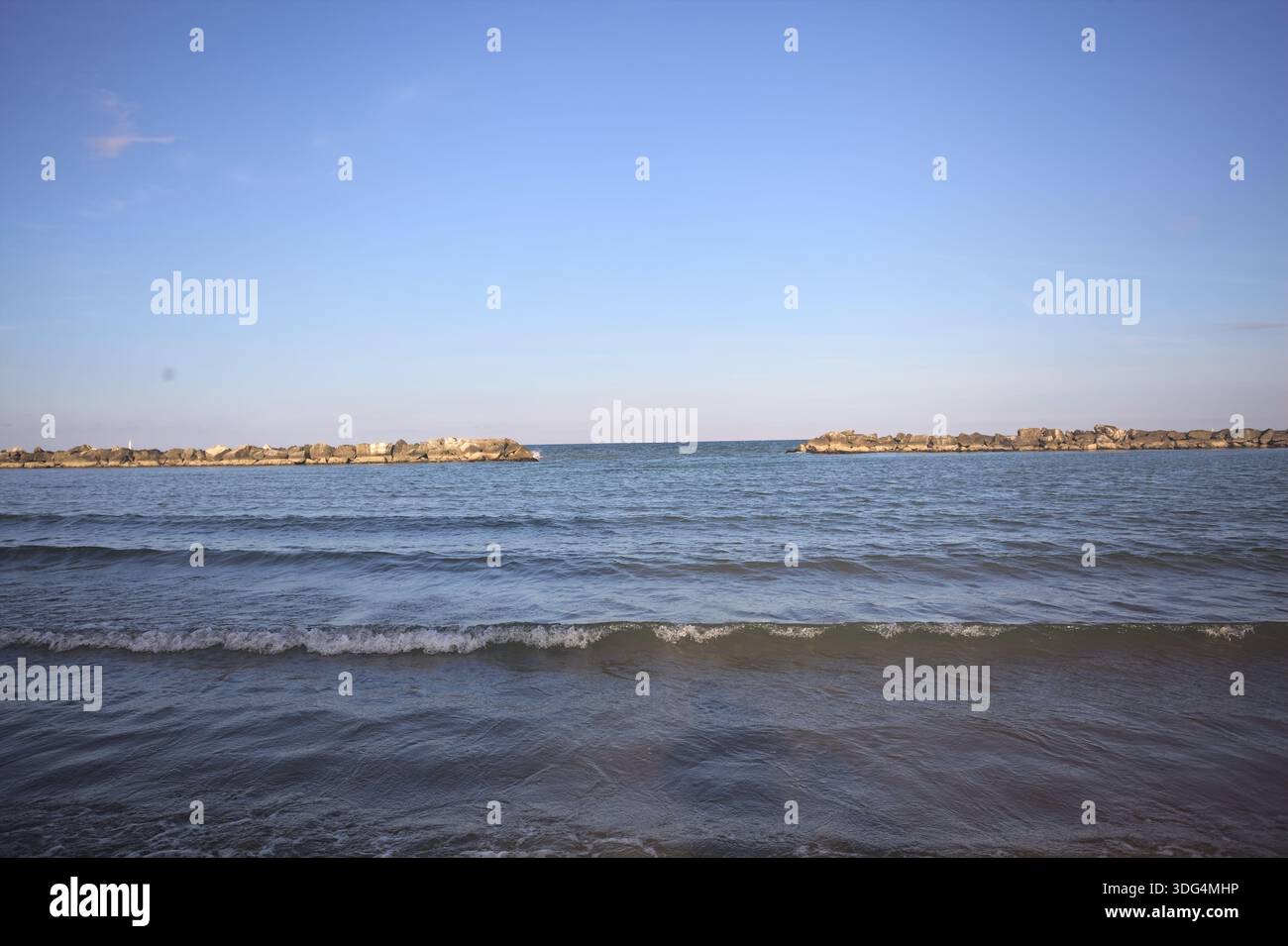 Breakwater on the horizon by the seaside at sunset Stock Photo - Alamy