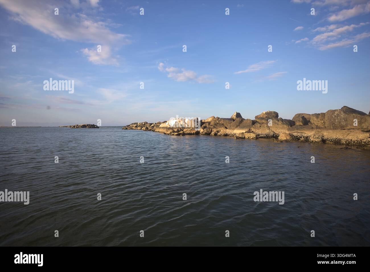 Breakwater near a beach by the seaside at sunset on a clear and sunny ...