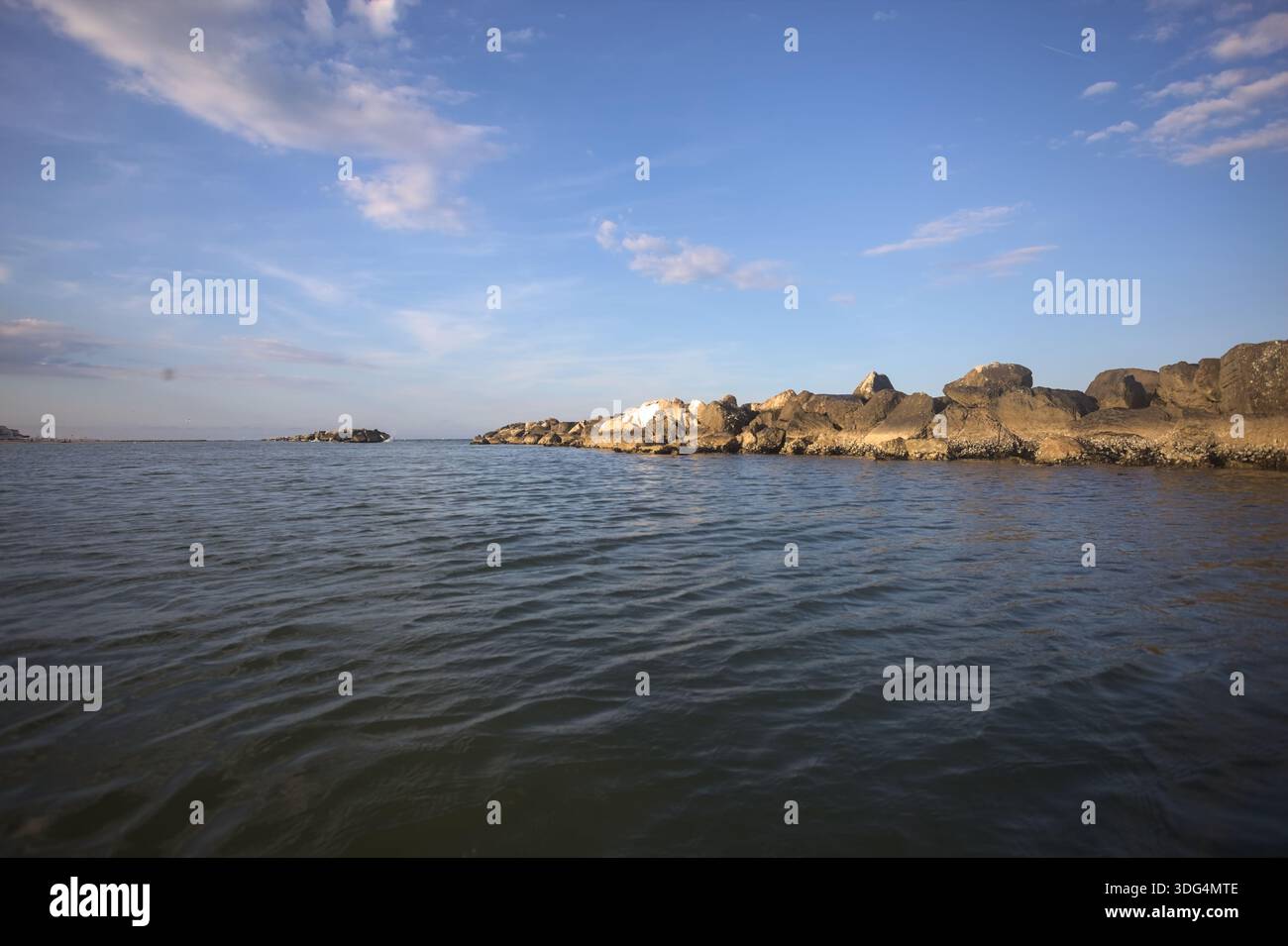 Breakwater near a beach by the seaside at sunset on a clear and sunny ...