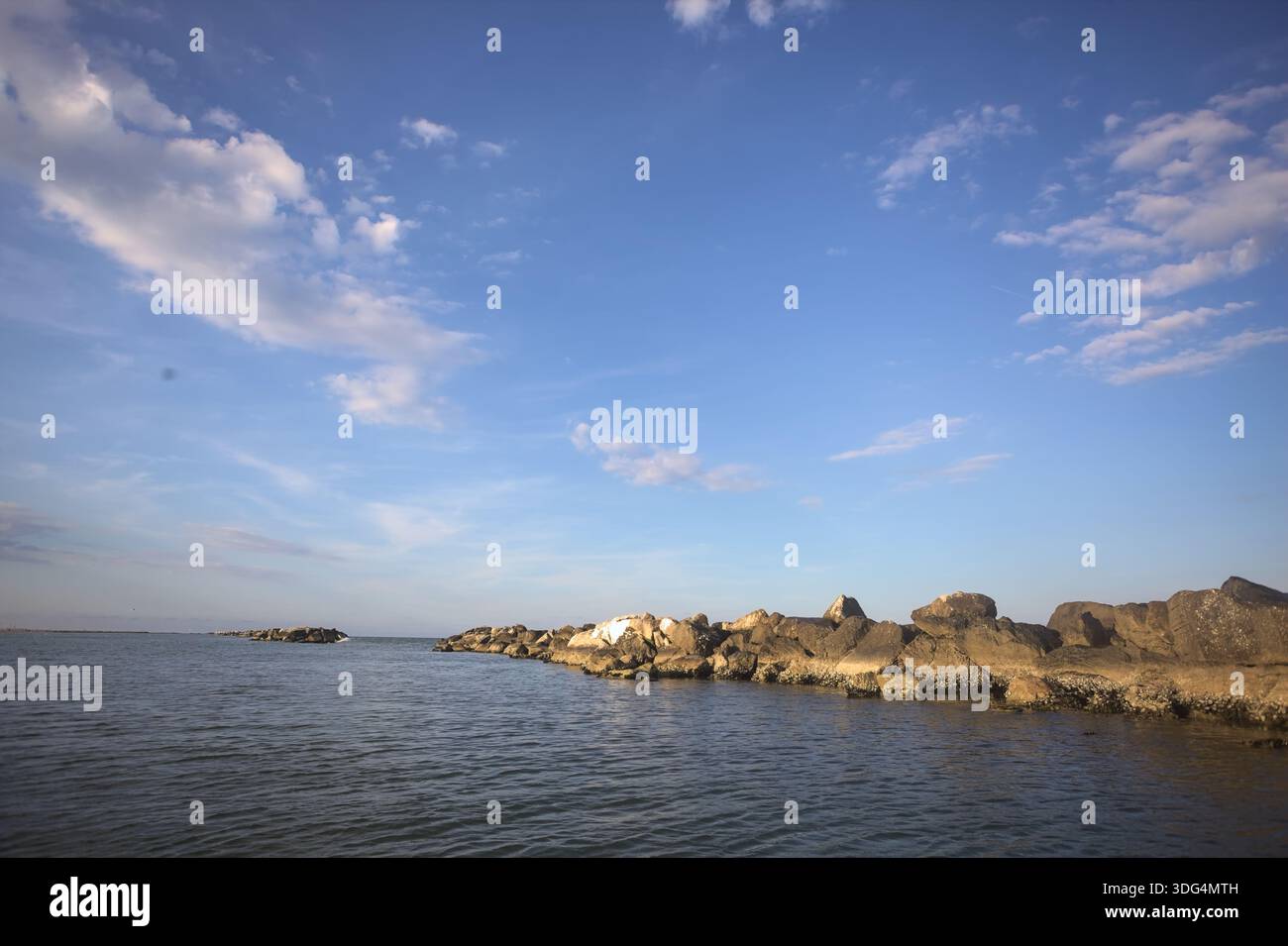 Breakwater near a beach by the seaside at sunset on a clear and sunny ...