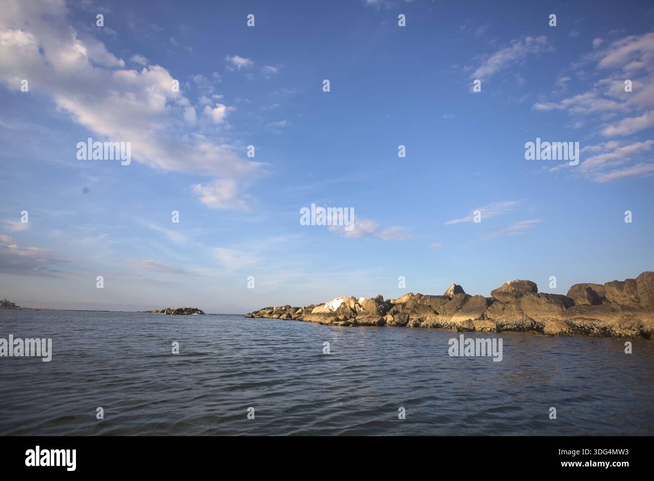 Breakwater near a beach by the seaside at sunset on a clear and sunny ...