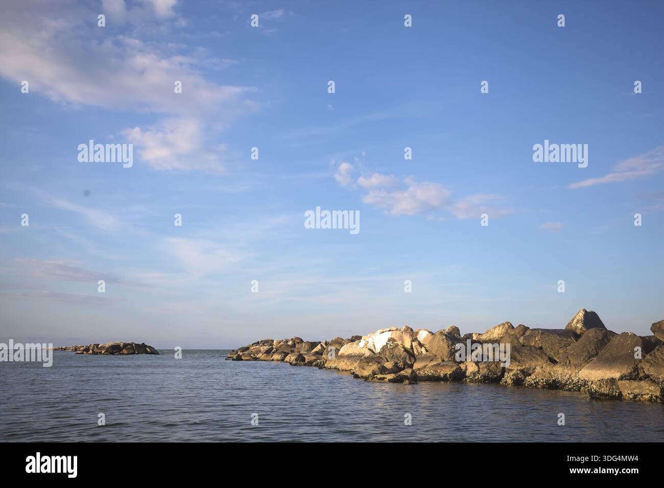 Breakwater near a beach by the seaside at sunset on a clear and sunny ...