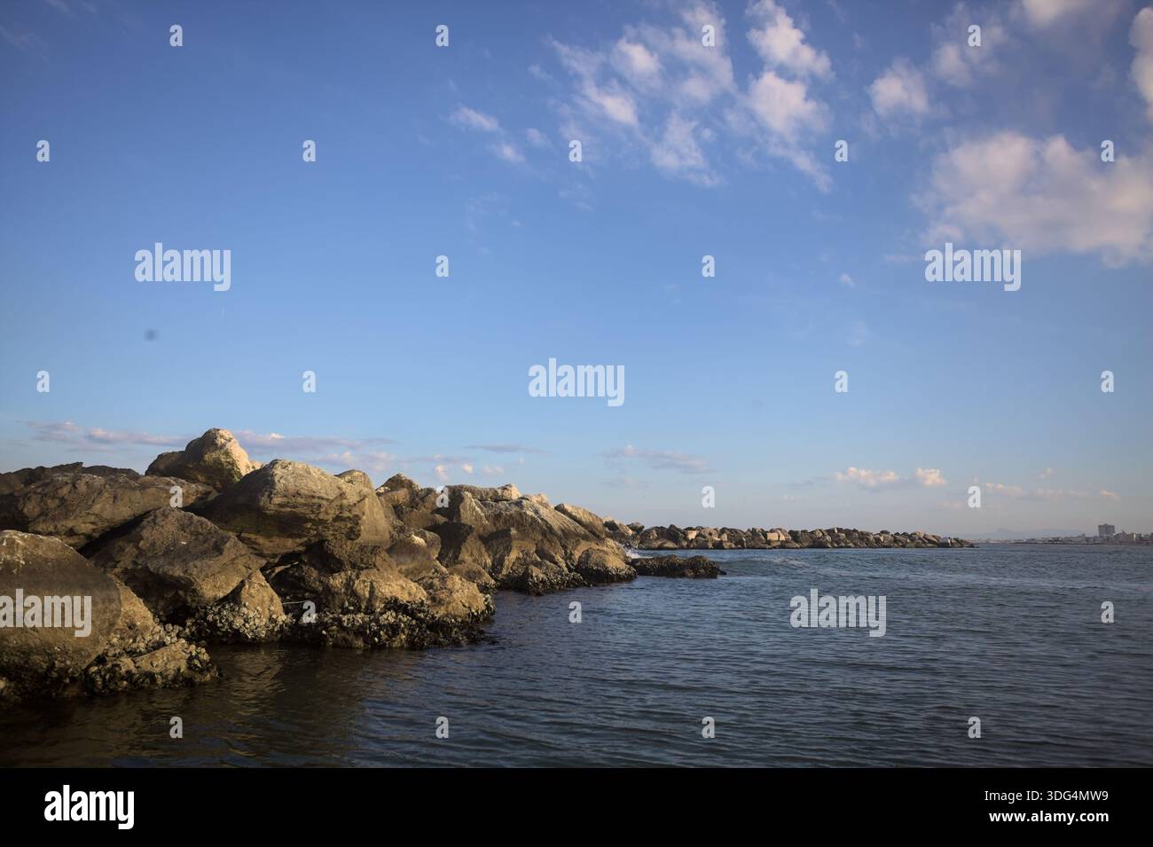 Breakwater near a beach by the seaside at sunset on a clear and sunny ...