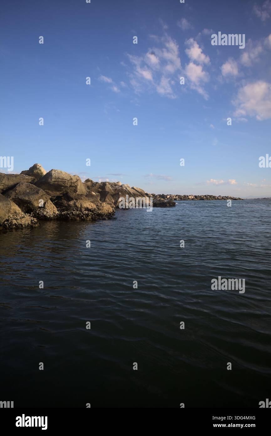 Breakwater near a beach by the seaside at sunset on a clear and sunny ...