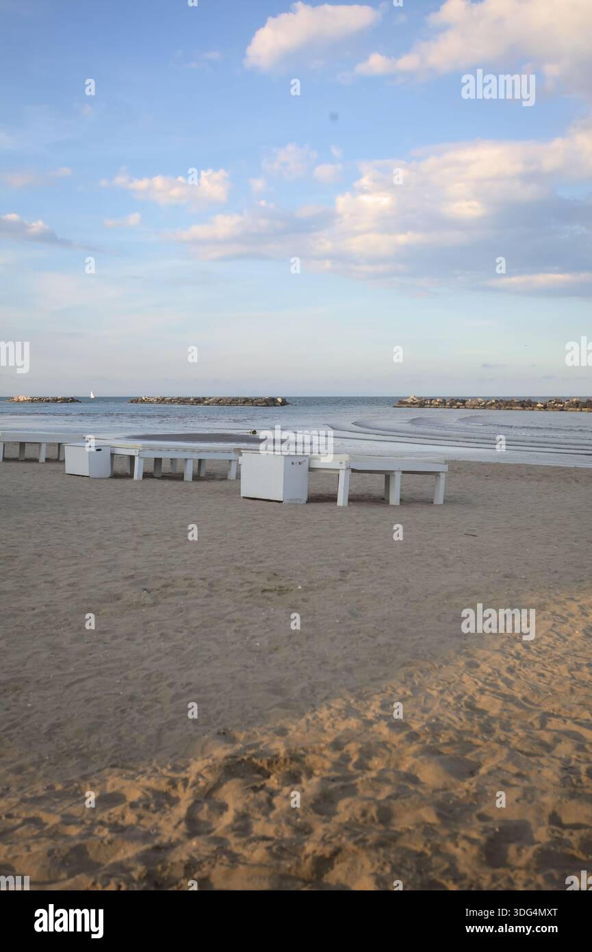 Empty deck chairs on a beach partially in the shade at sunset Stock ...