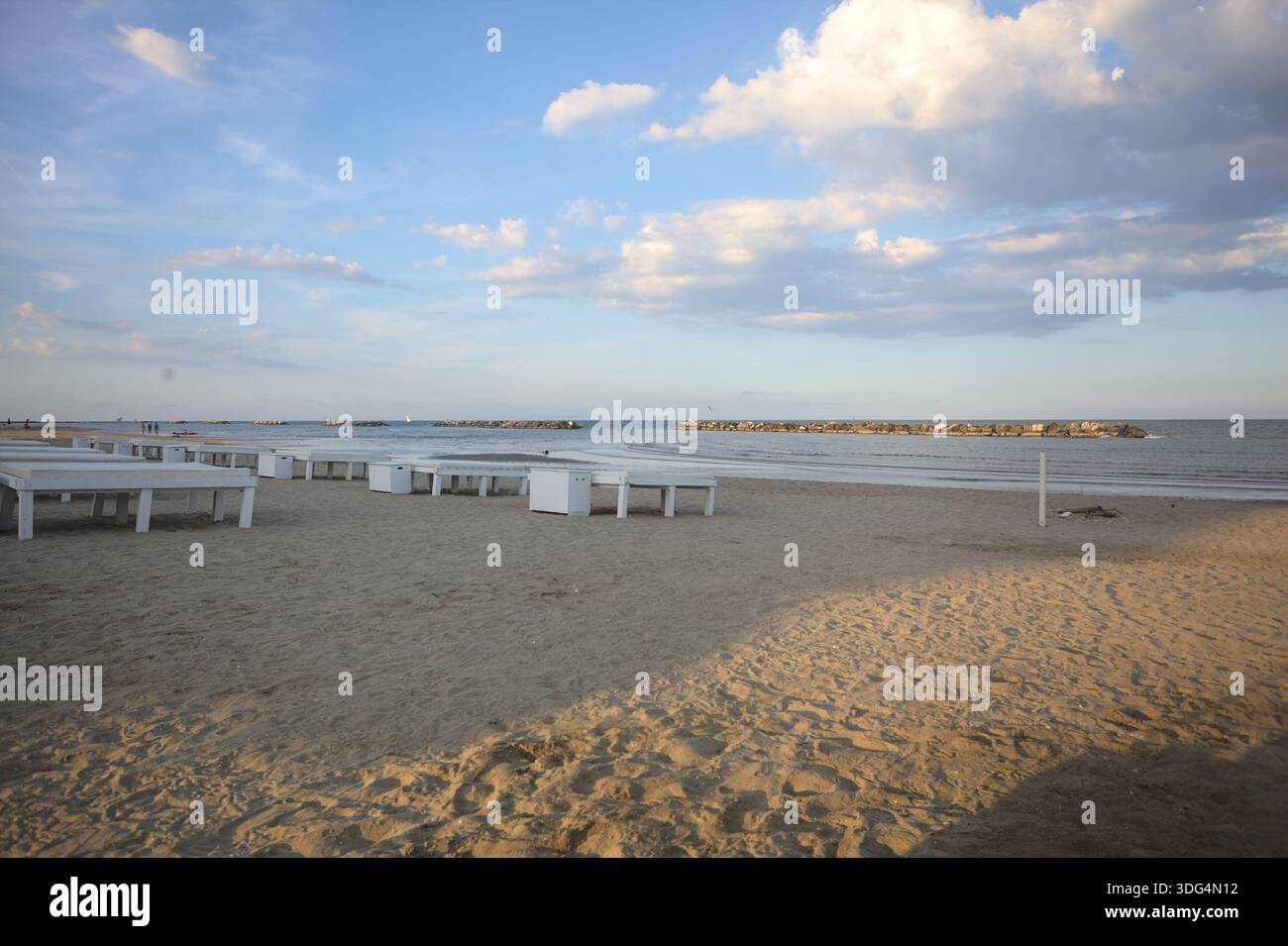 Empty deck chairs on a beach partially in the shade at sunset Stock ...