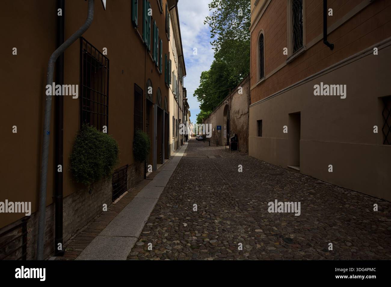 Narrow cobbled alley partially in the shade in an italian town seen ...