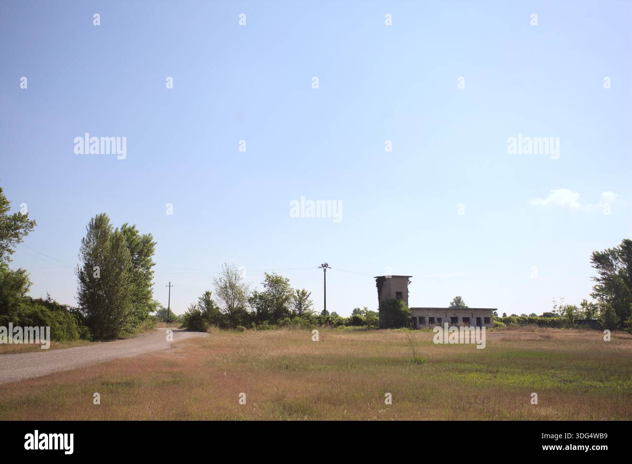Dirt road blocked by a rusty bar next to a yard with dry grass and ...