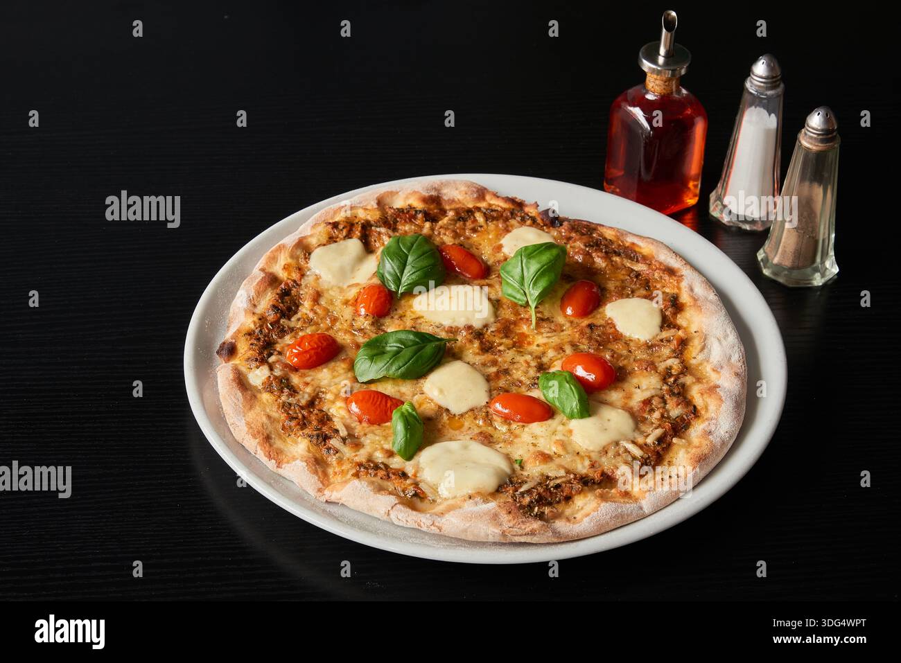 A plate of Margherita pizza and basil on black wooden table Stock Photo ...