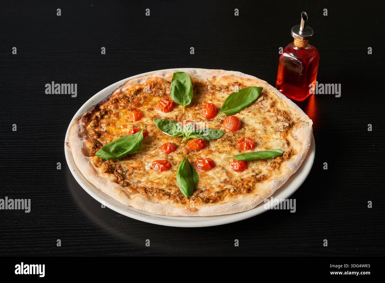 A plate of Margherita pizza and basil on black wooden table Stock Photo ...