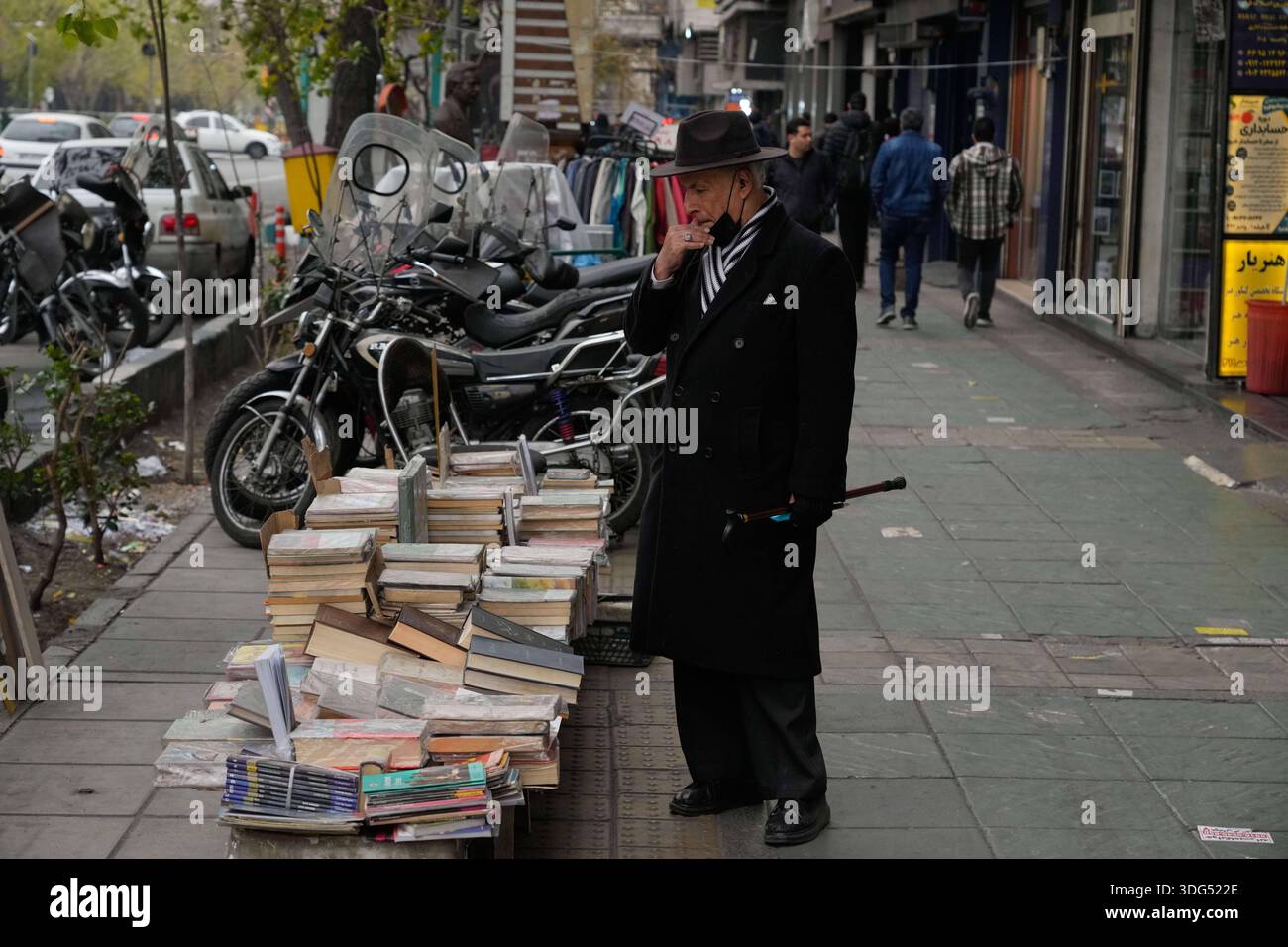 A man looks at books which are placed for sale on a sidewalk in ...