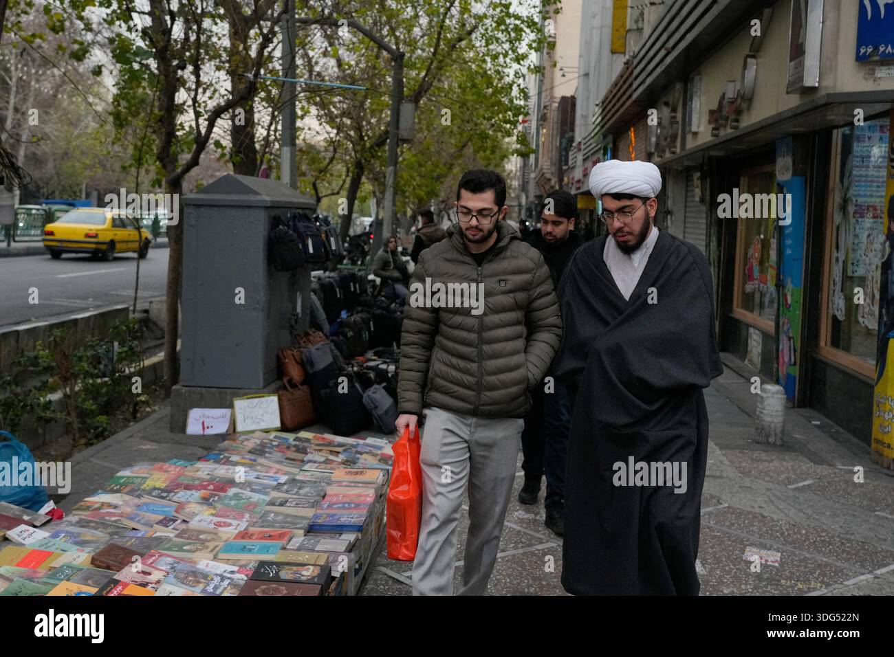 A cleric and other people walk on a sidewalk in downtown Tehran, Iran ...