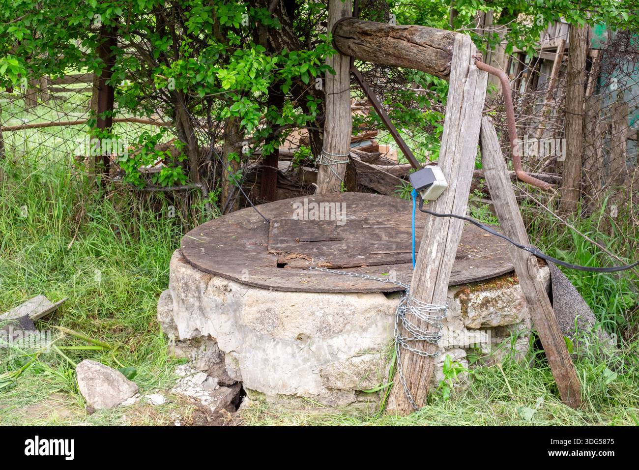 An old rustic well with a wooden cover and a hand crank mechanism in a ...