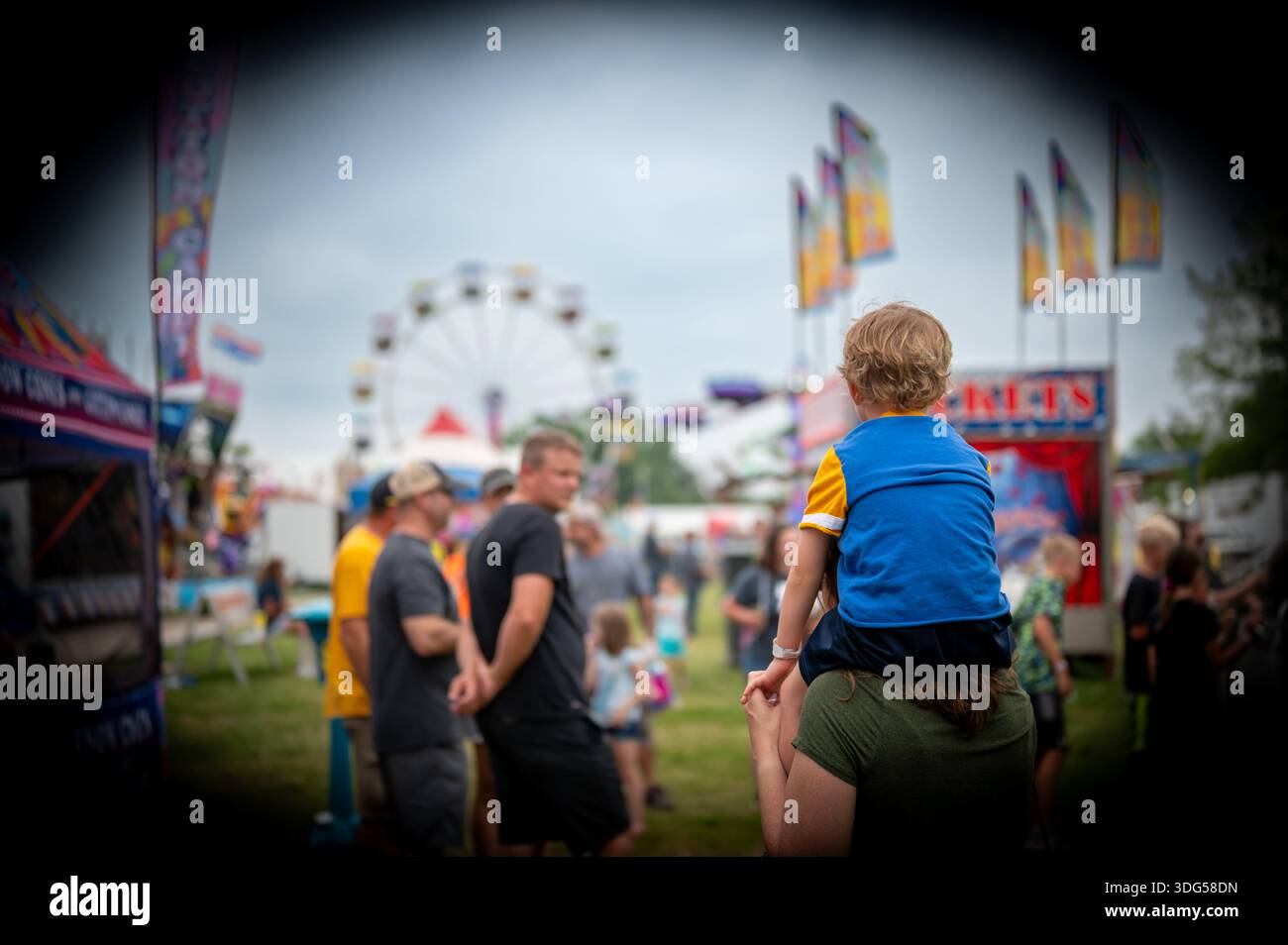 Child enjoys a carnival atmosphere from a parent's shoulders while ...