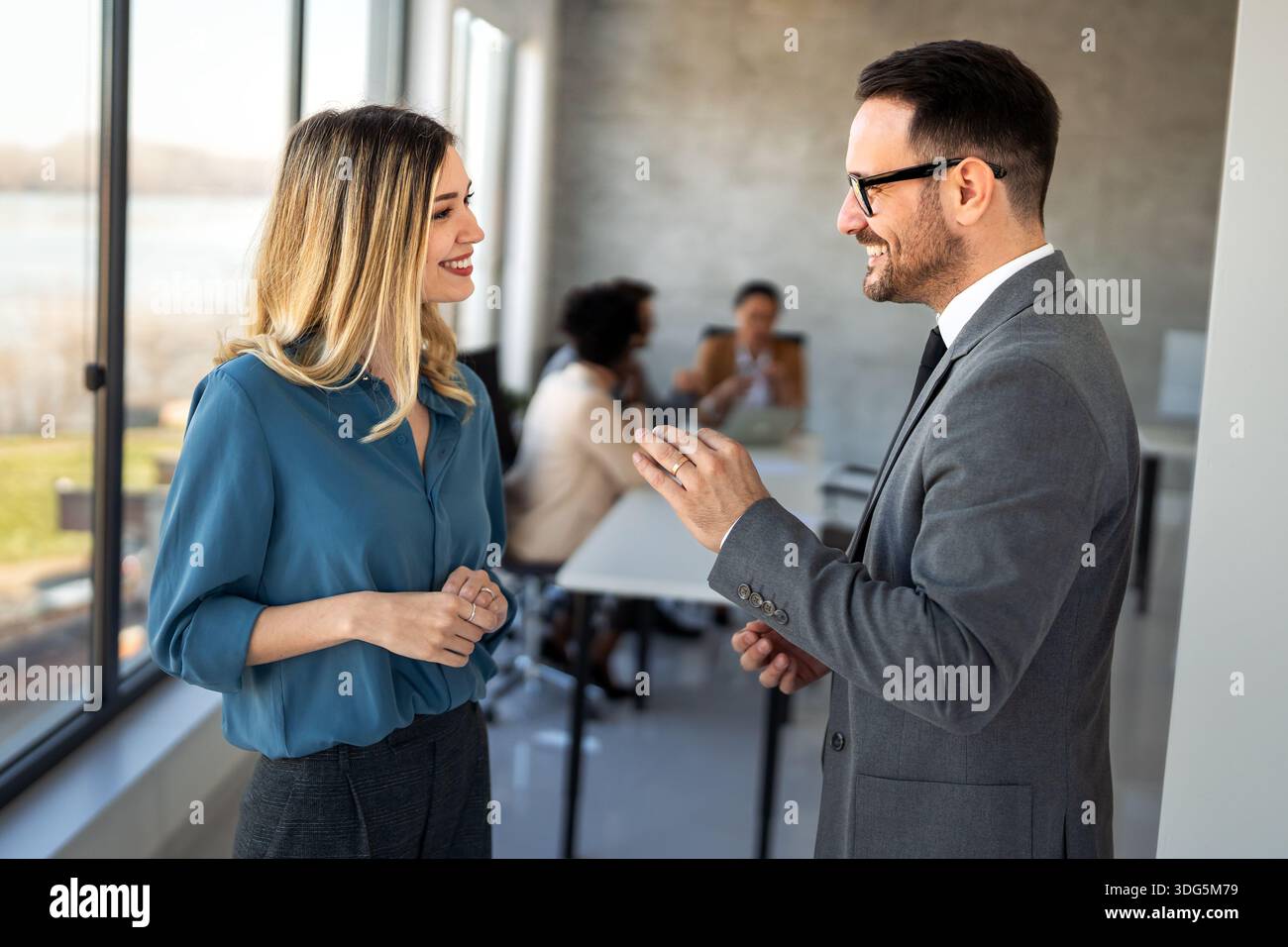 Professionals in a modern office environment discussing work-related ...