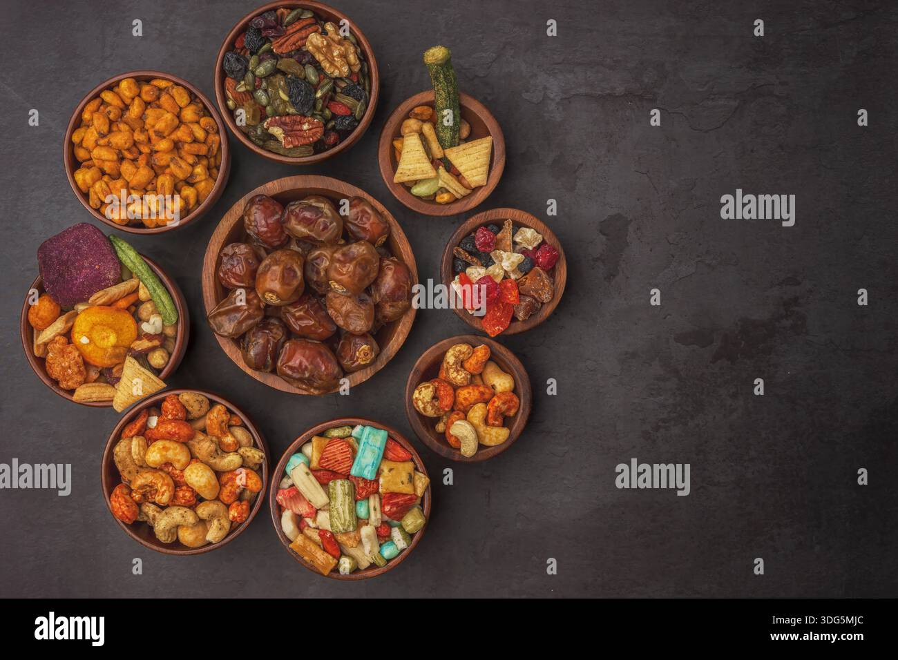 Different types of nuts, seeds and dried fruits on black background ...