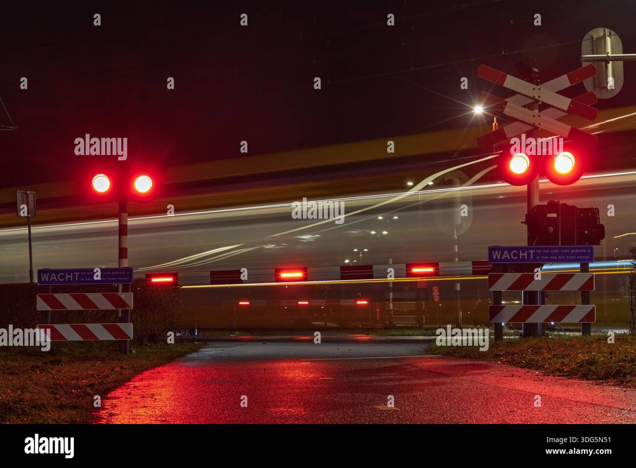 Railroad crossing with red warning lights and barrier while a tram ...