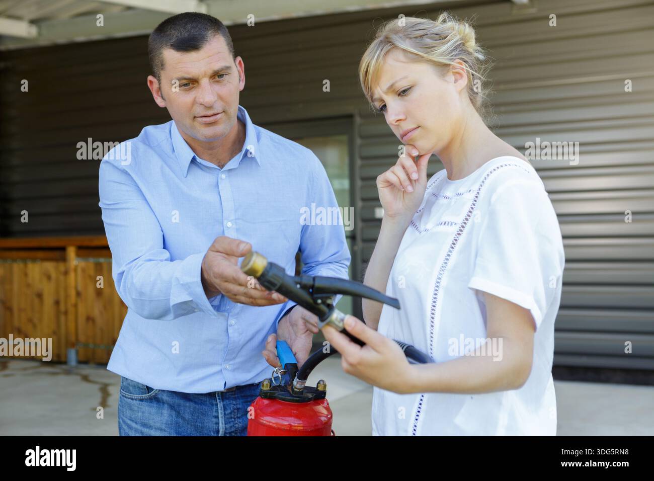 man showing woman how to use a fire extinguisher Stock Photo - Alamy