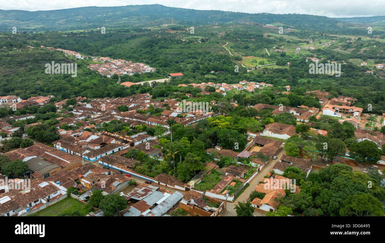 Aerial view of a small town with red rooftops surrounded by lush green ...