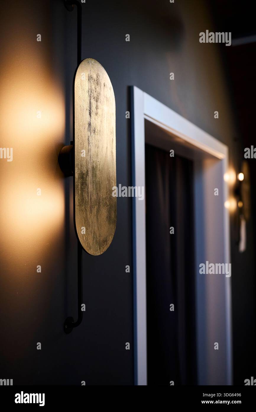 Elegant wall-mounted lamp in a dark interior, featuring a golden design ...