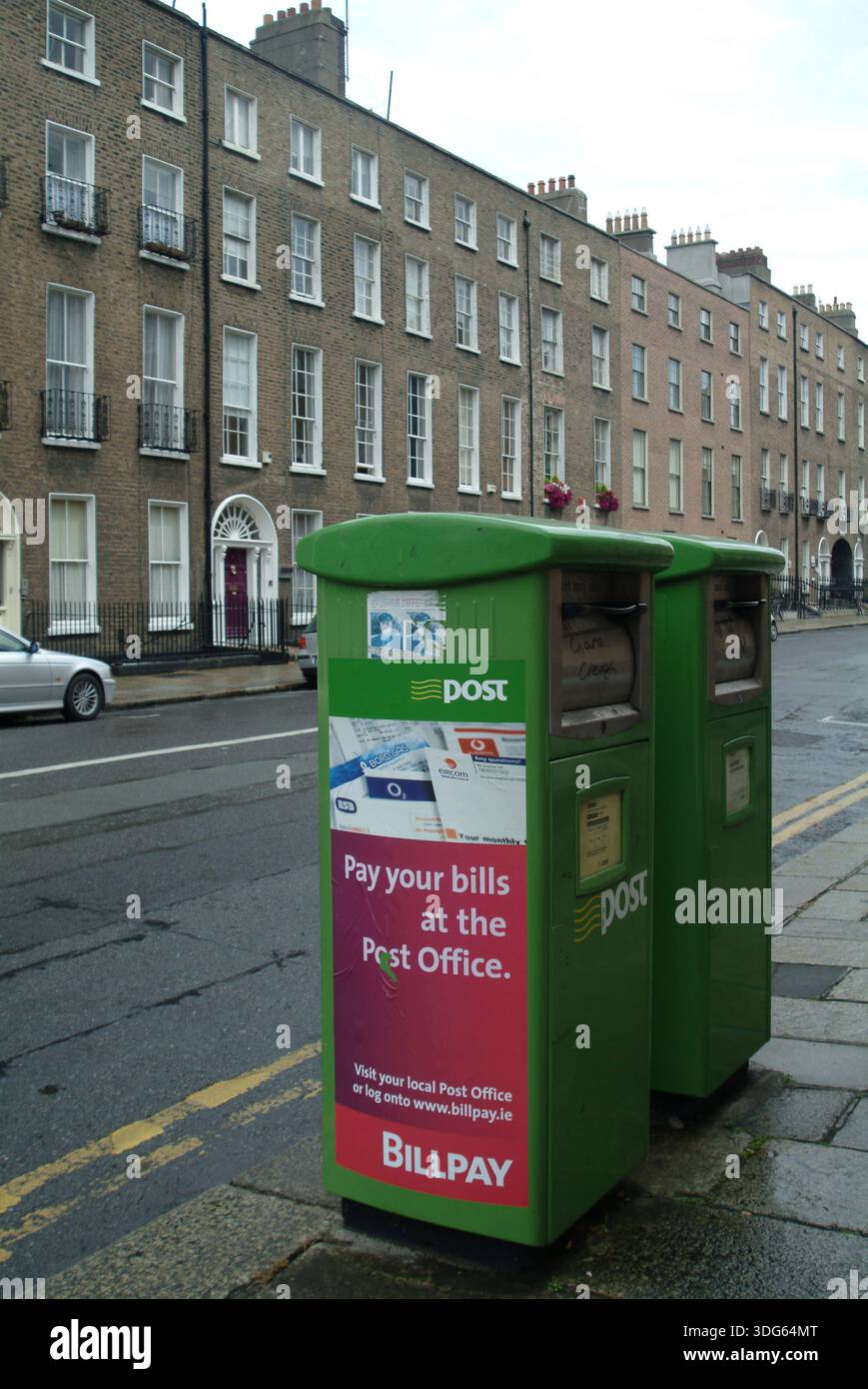 A traditional green Irish post box standing alone on a quiet Dublin ...