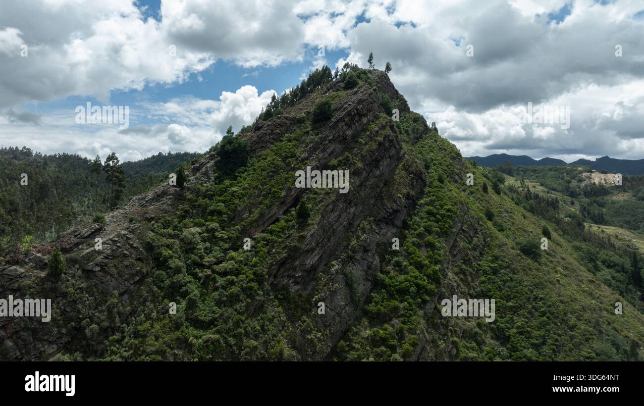 A lush, green mountain peak under a sky filled with dramatic clouds ...