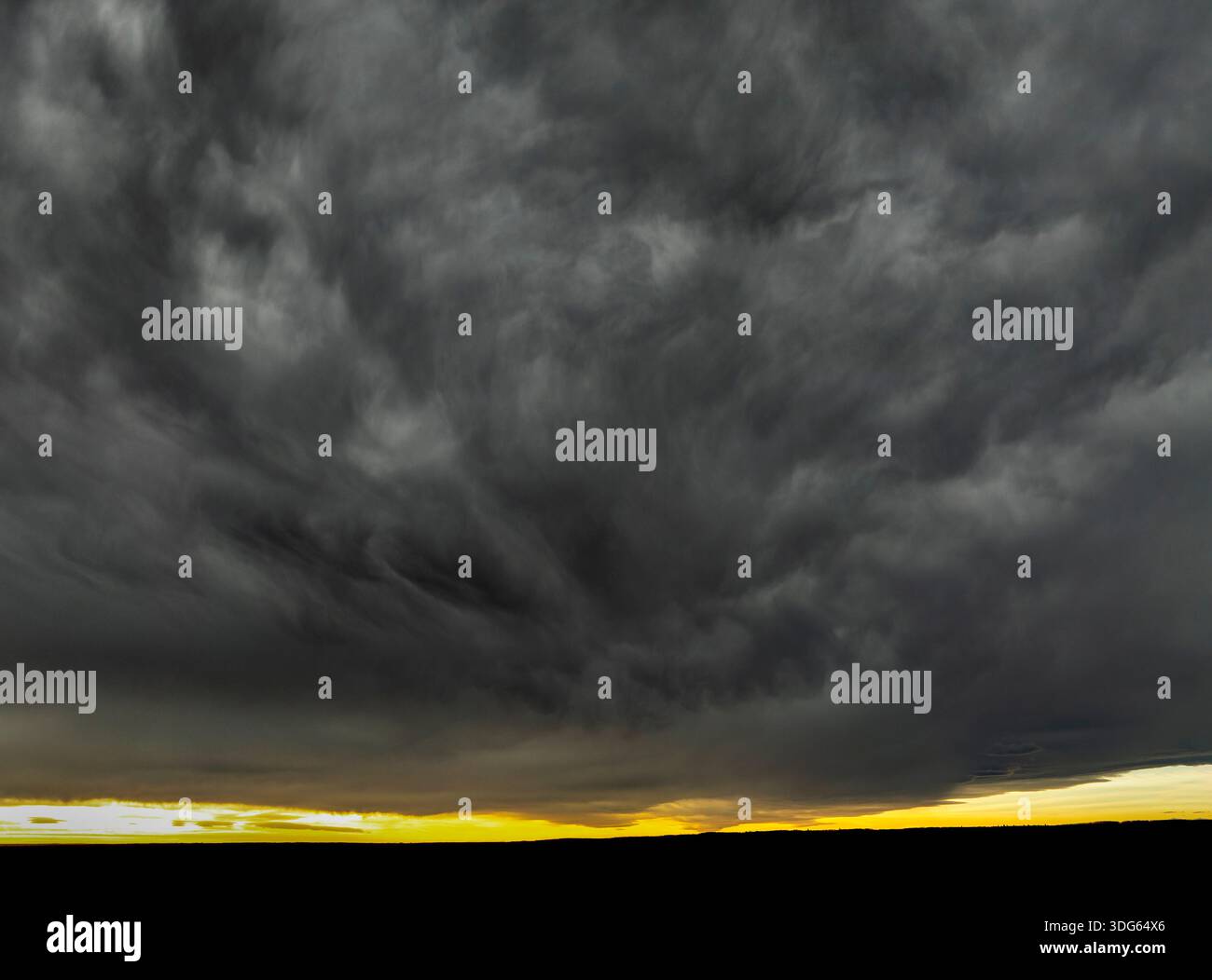 Dark storm clouds swirl dramatically above a yellow horizon during ...