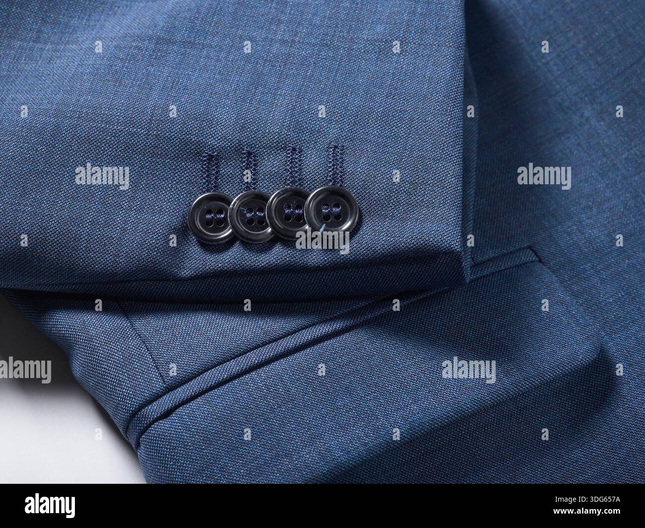 Close-up of a navy blue suit sleeve with four black buttons on a white ...