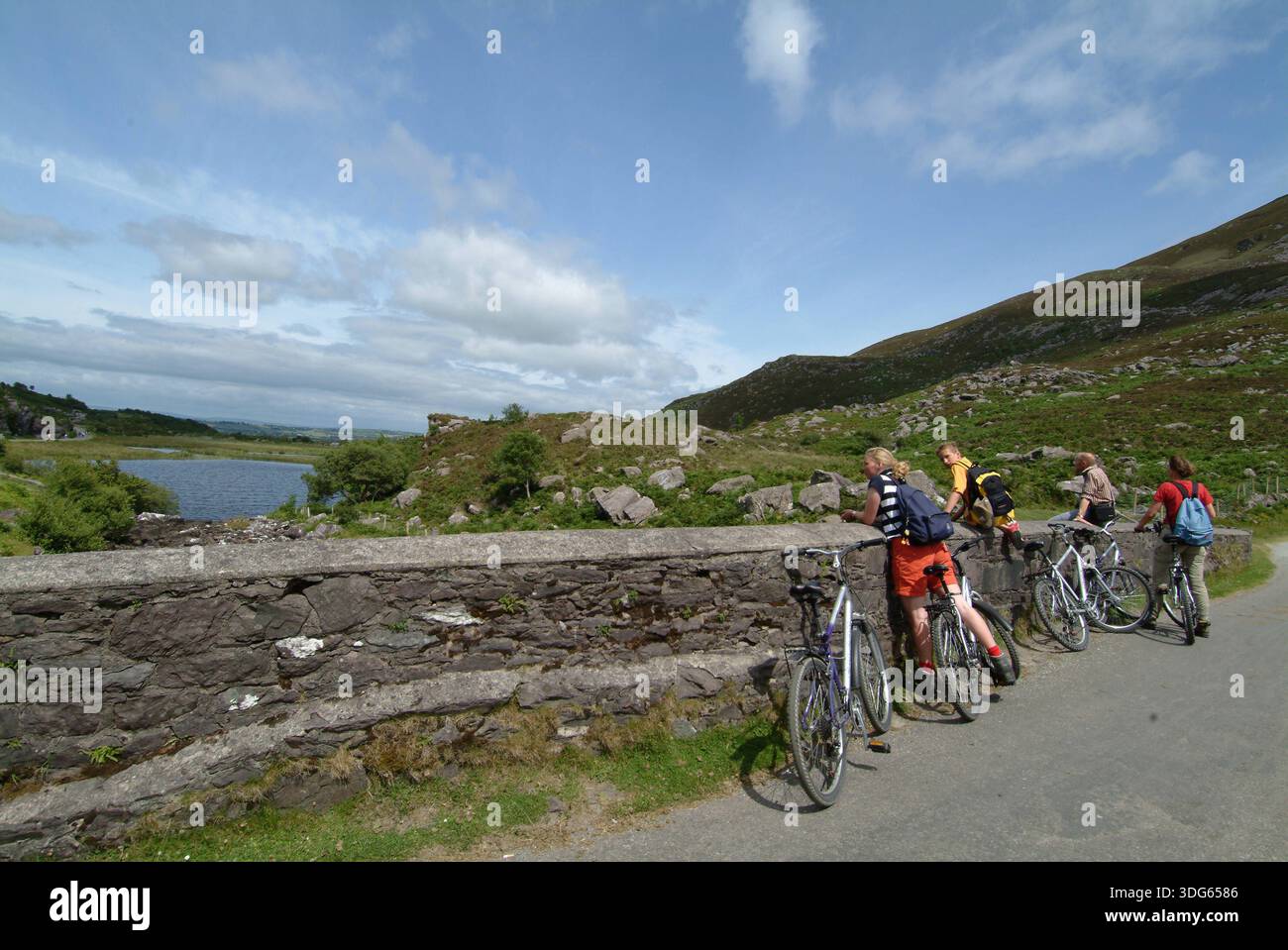 Cyclists resting on stone wall, Gap of Dunloe. - County Kerry, Ireland ...