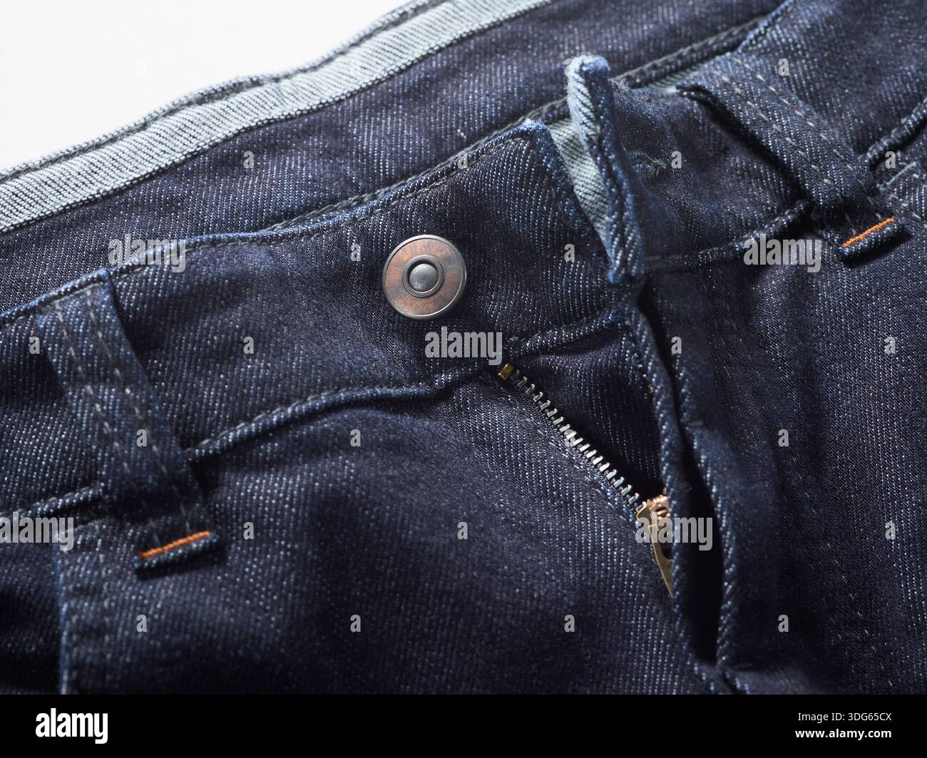 Close-up of blue denim jeans with a visible button and partly open ...