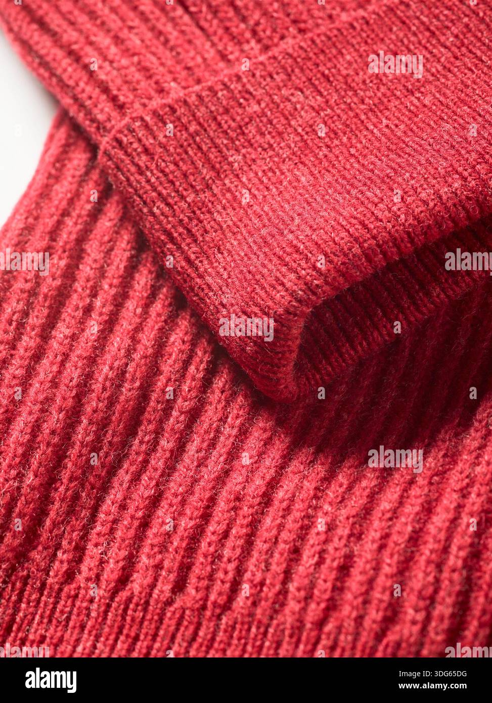Close-up of folded red knitted fabric with vertical ribbed texture ...