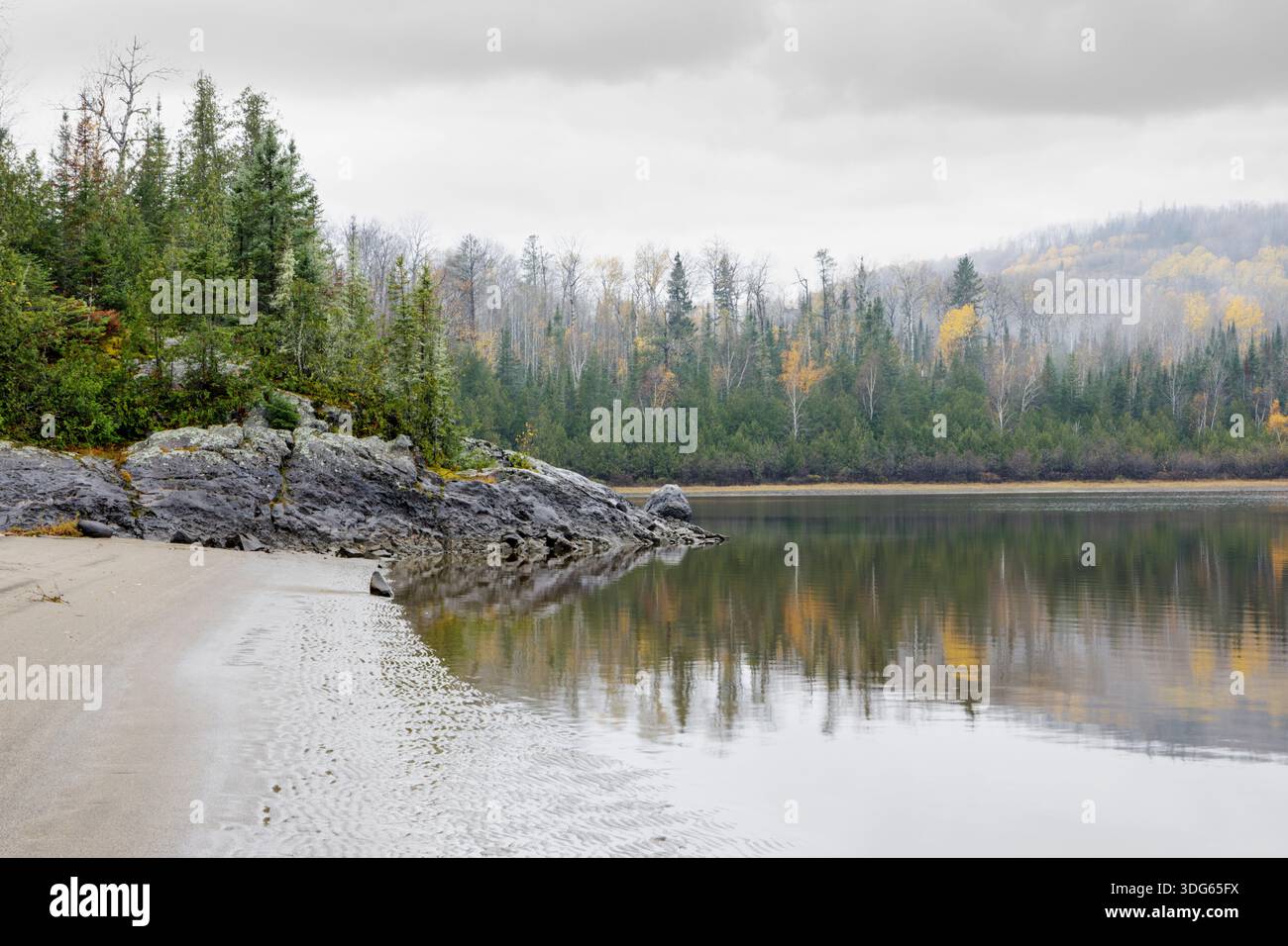 Tranquil lakeside with rocky shore, pine forest, and autumn foliage ...