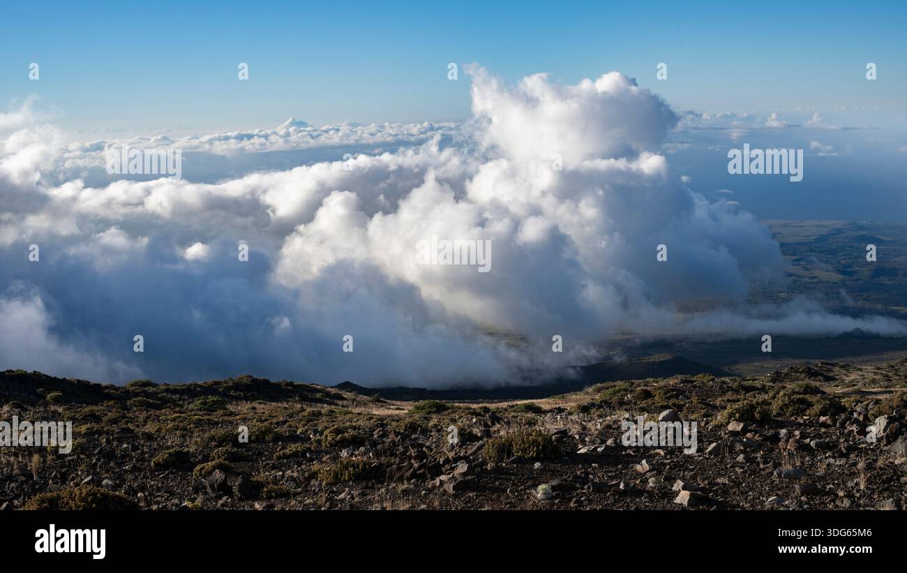 Expansive view of fluffy clouds over rugged mountain terrain under a ...