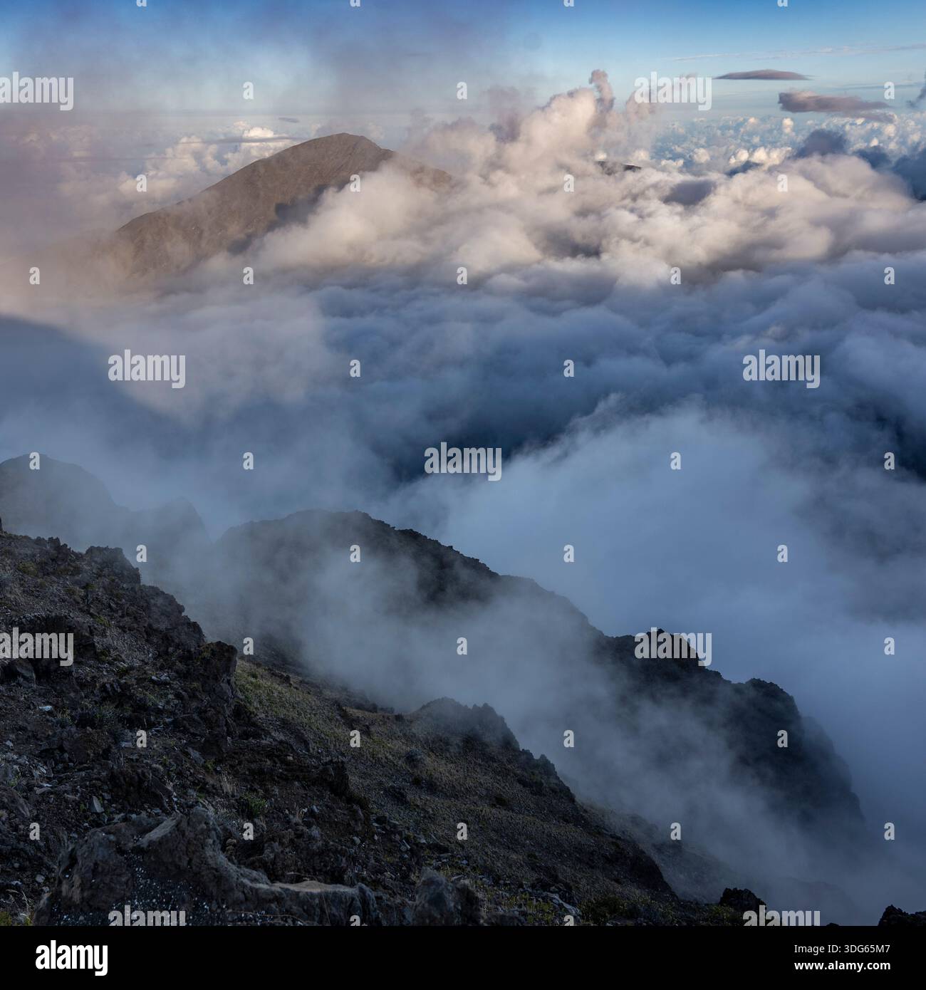 Misty mountain landscape with clouds hovering over rocky peaks and a ...