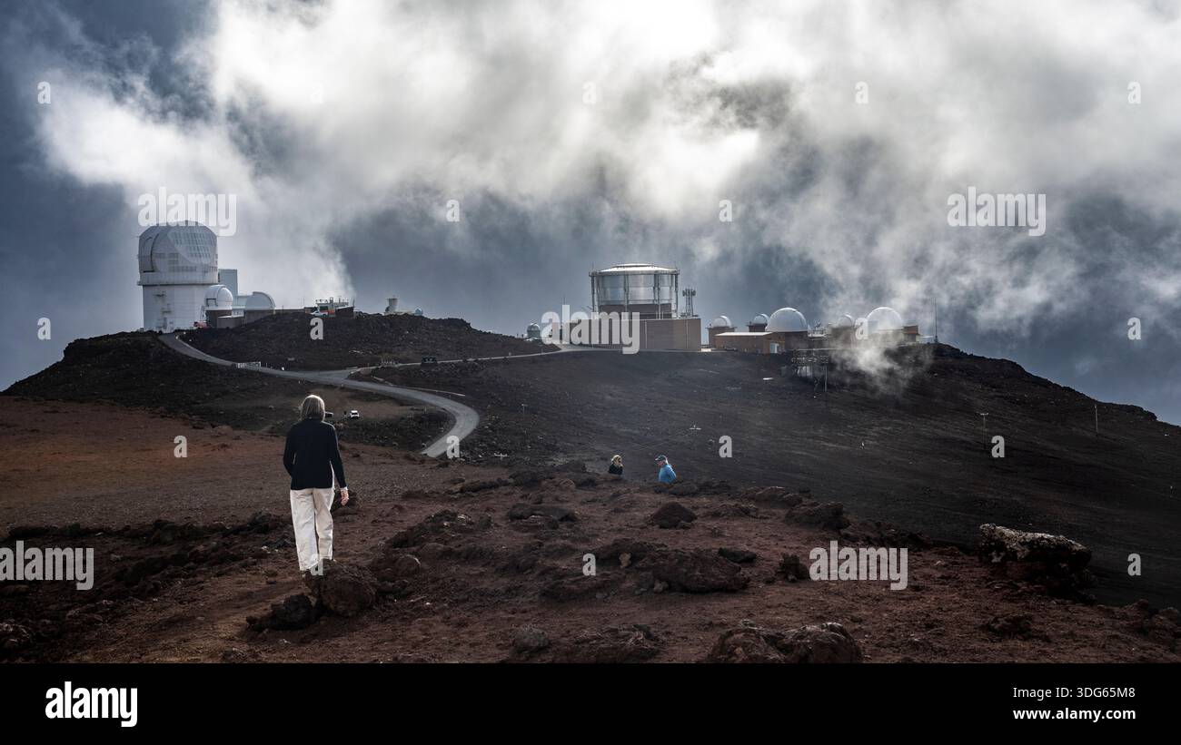 Observatory buildings on a rocky hill under dramatic clouds with people ...