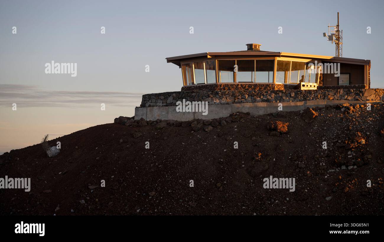 A solitary hilltop building with large windows under a clear sky at ...