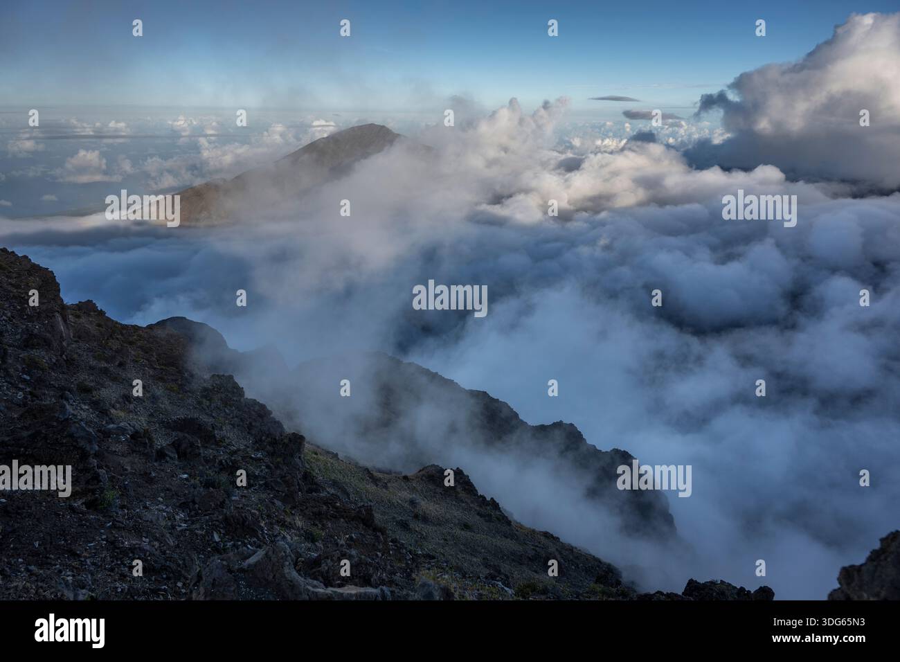 Dramatic mountain peaks piercing through a sea of clouds under a vivid ...