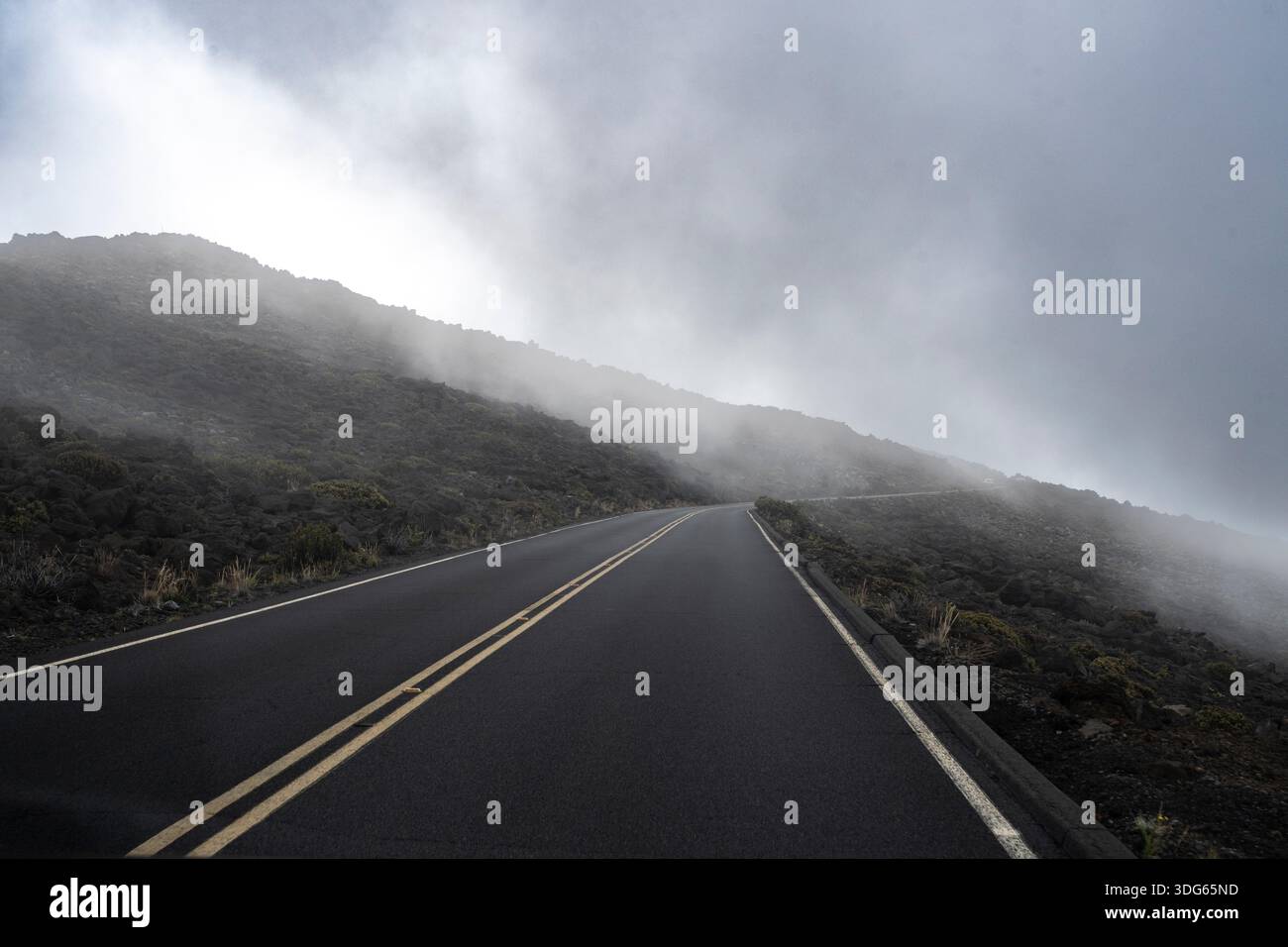 Misty mountain road with fog and low clouds creating a mysterious and ...