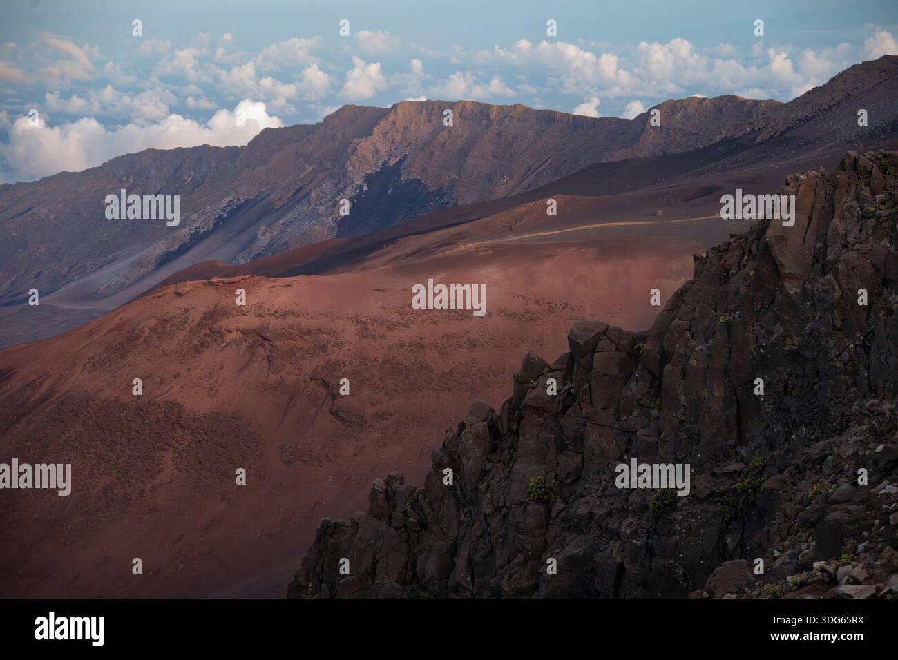 Rugged volcanic landscape with rocky ridges under a cloudy sky at dusk ...