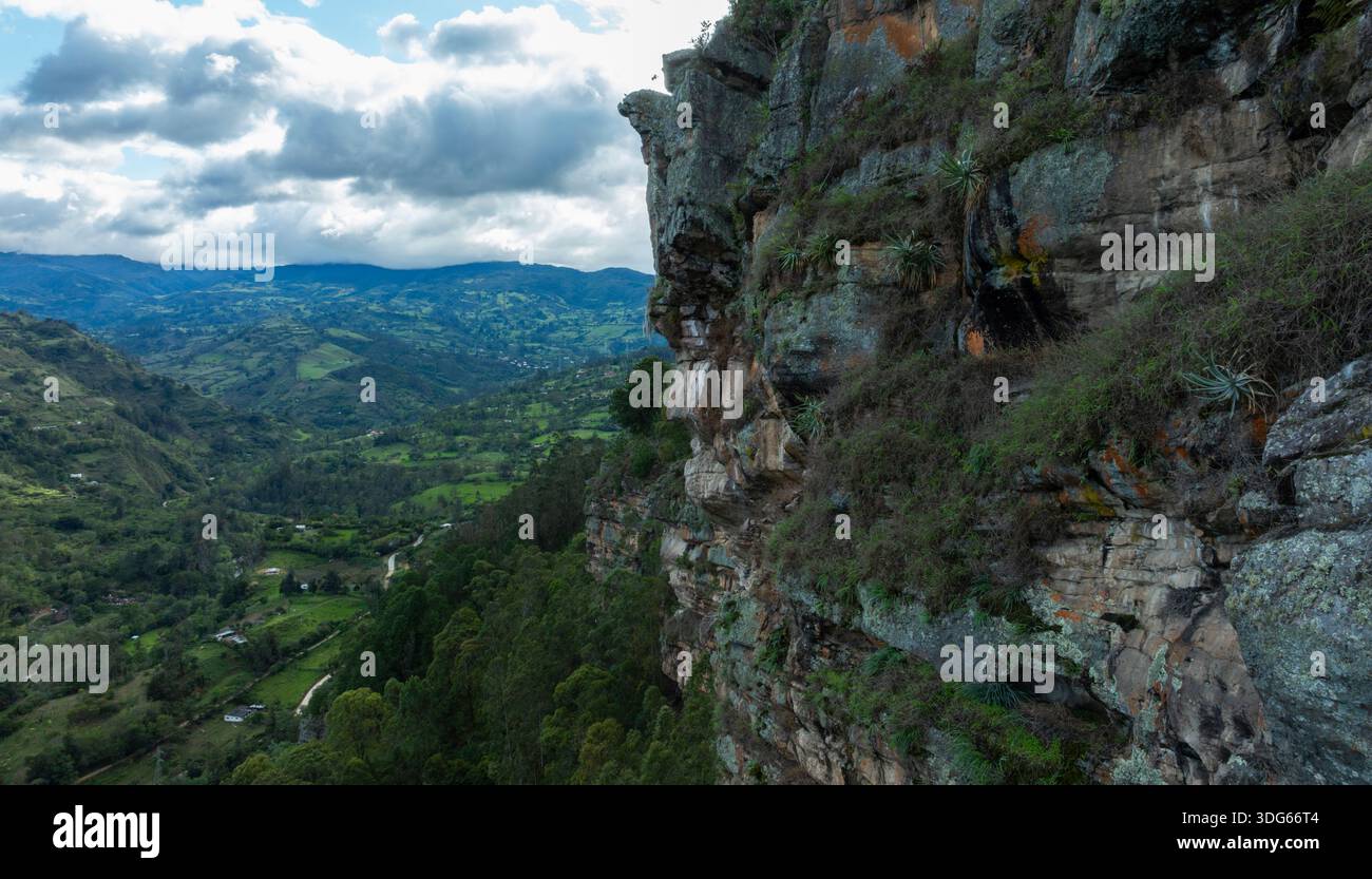 Dramatic cliffside view overlooking lush green valley under a cloudy ...